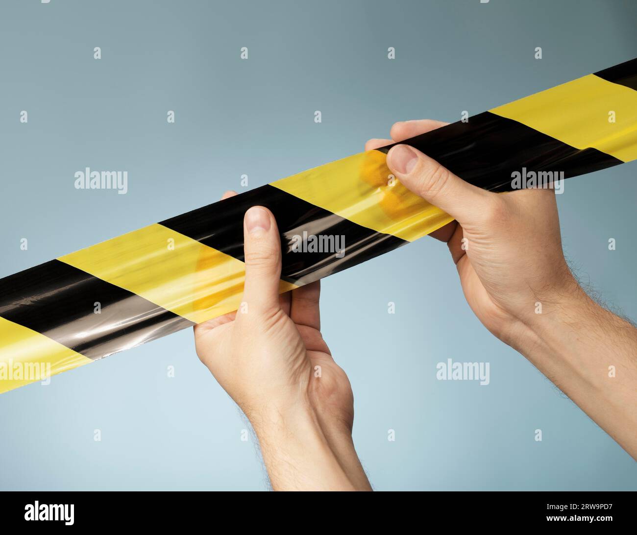 Man holding black and yellow striped barrier tape in his hands Stock ...