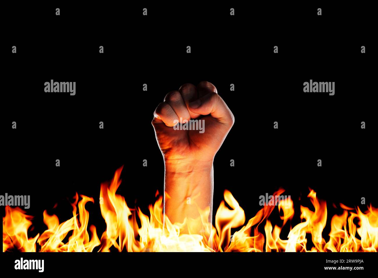 Hand in a fist emerging from a sea of fire Stock Photo - Alamy