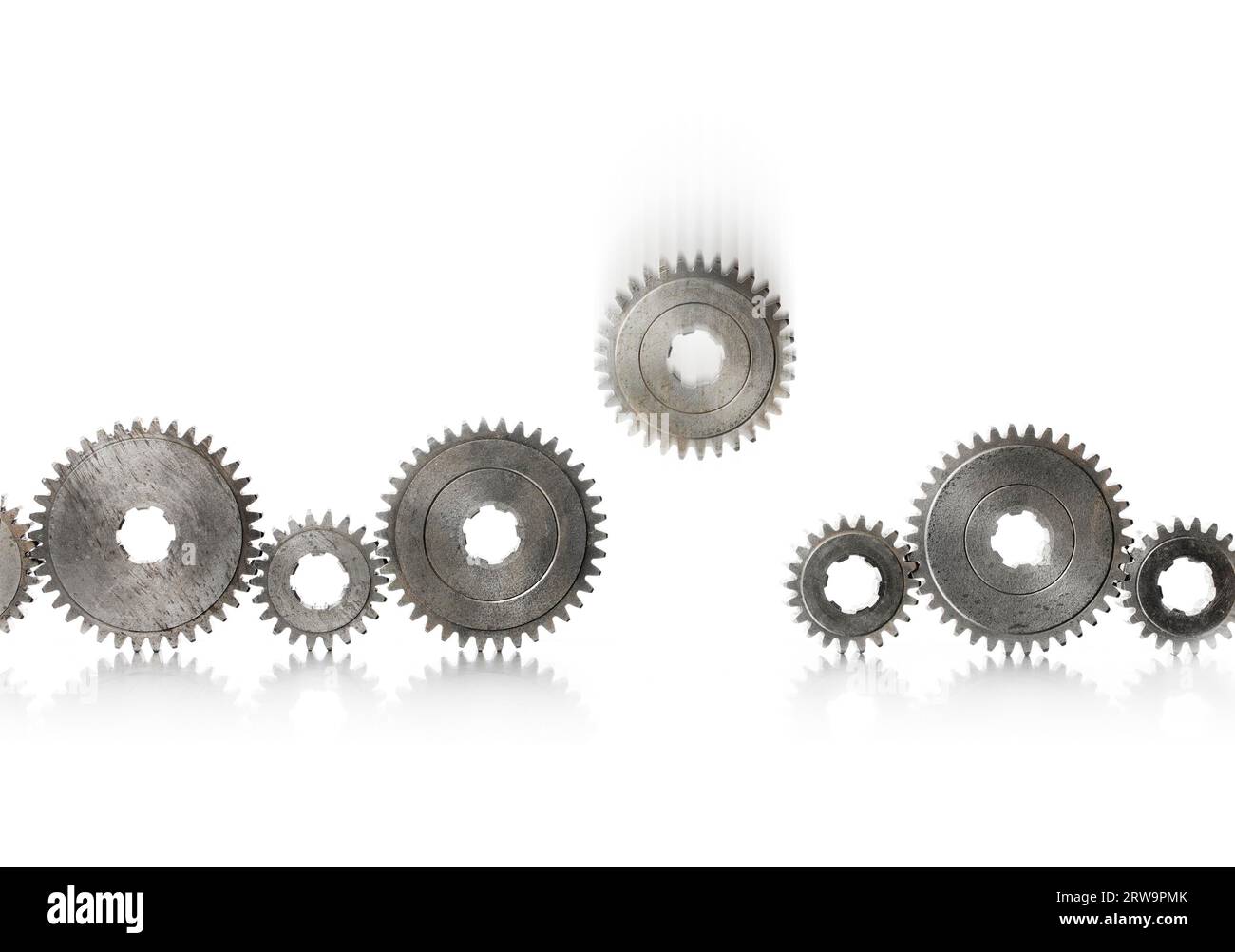 A row of old metallic cog gears being filled with one blurry falling ...