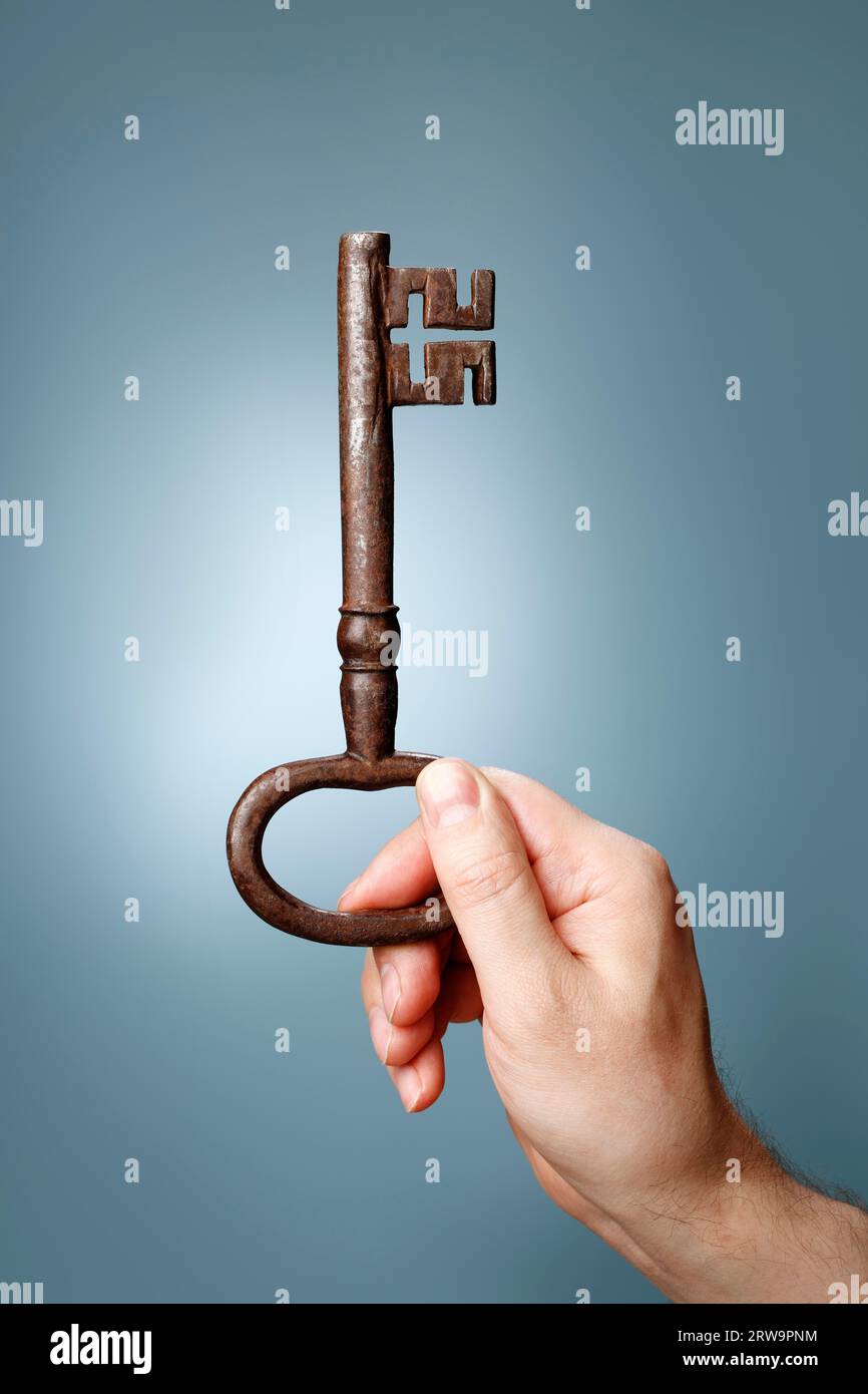 Man holding a big old key in his hand Stock Photo - Alamy
