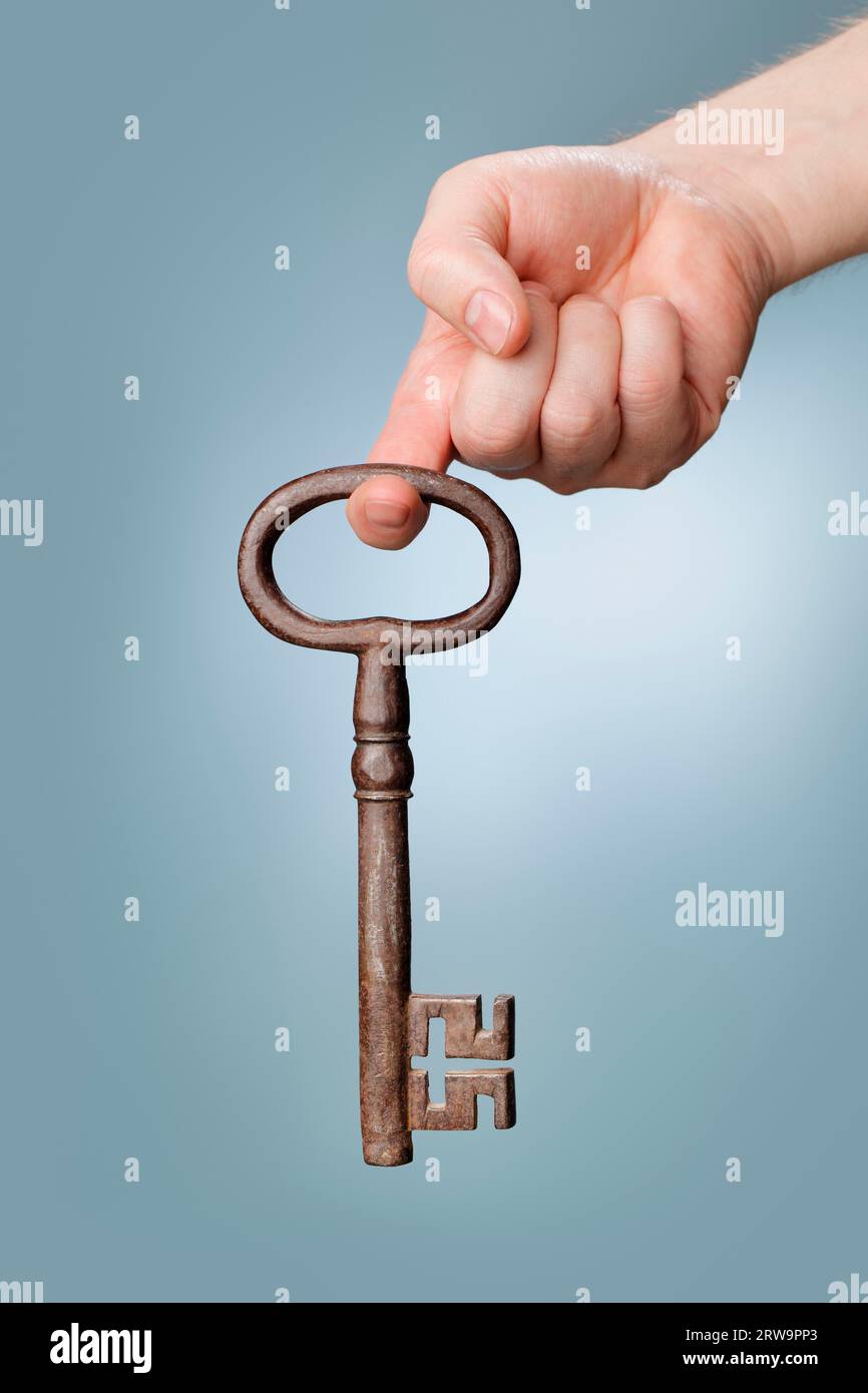 A Large old antique skeleton key hanging from a finger Stock Photo - Alamy