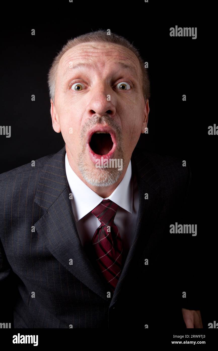 Mature businessman shouting at camera. Black background Stock Photo - Alamy