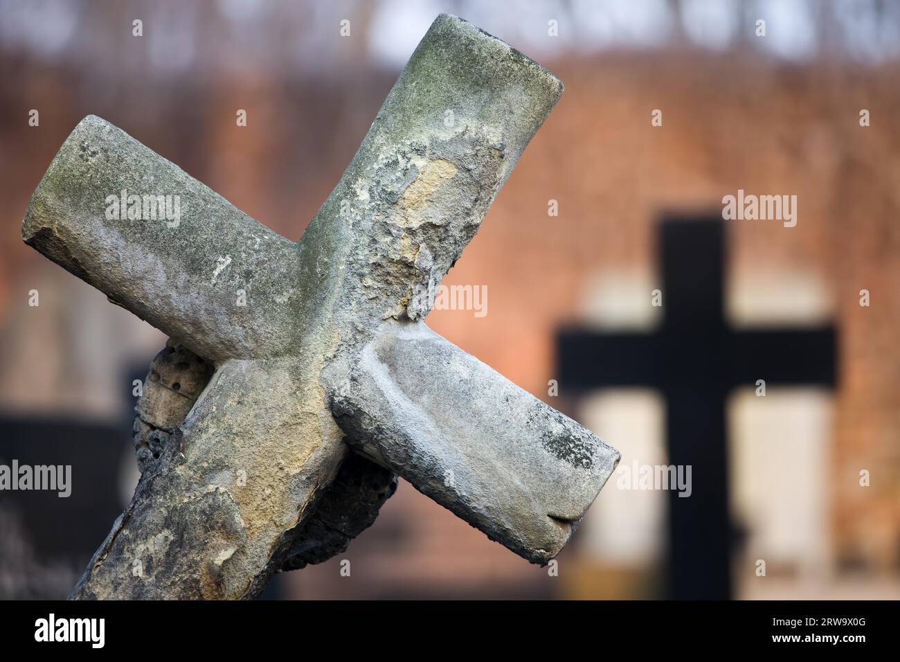 An old 19th century leaning gravestone cross at cemetery, blurred ...