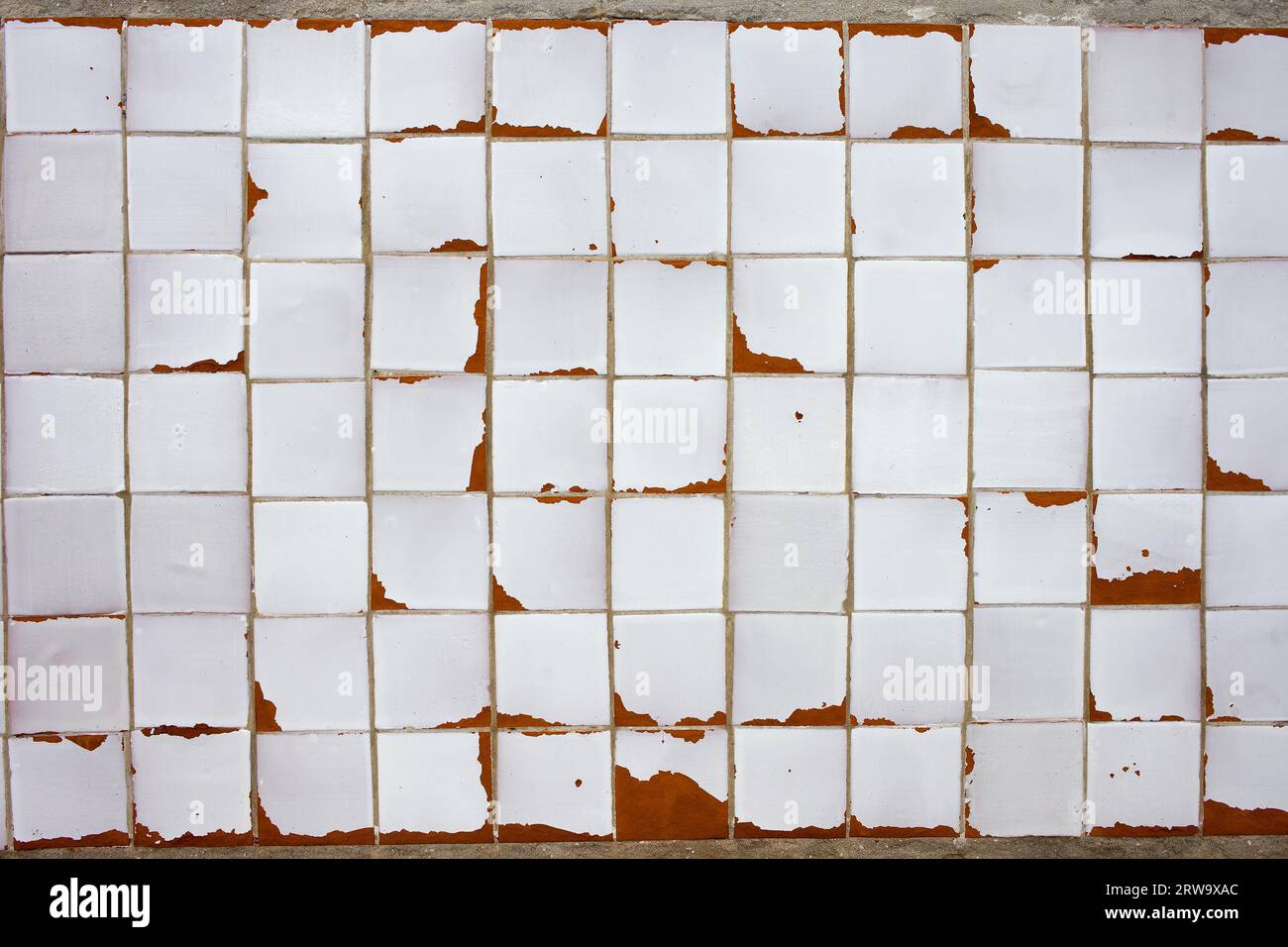 An old white obsolete and damaged tiled wall, good as a texture or ...