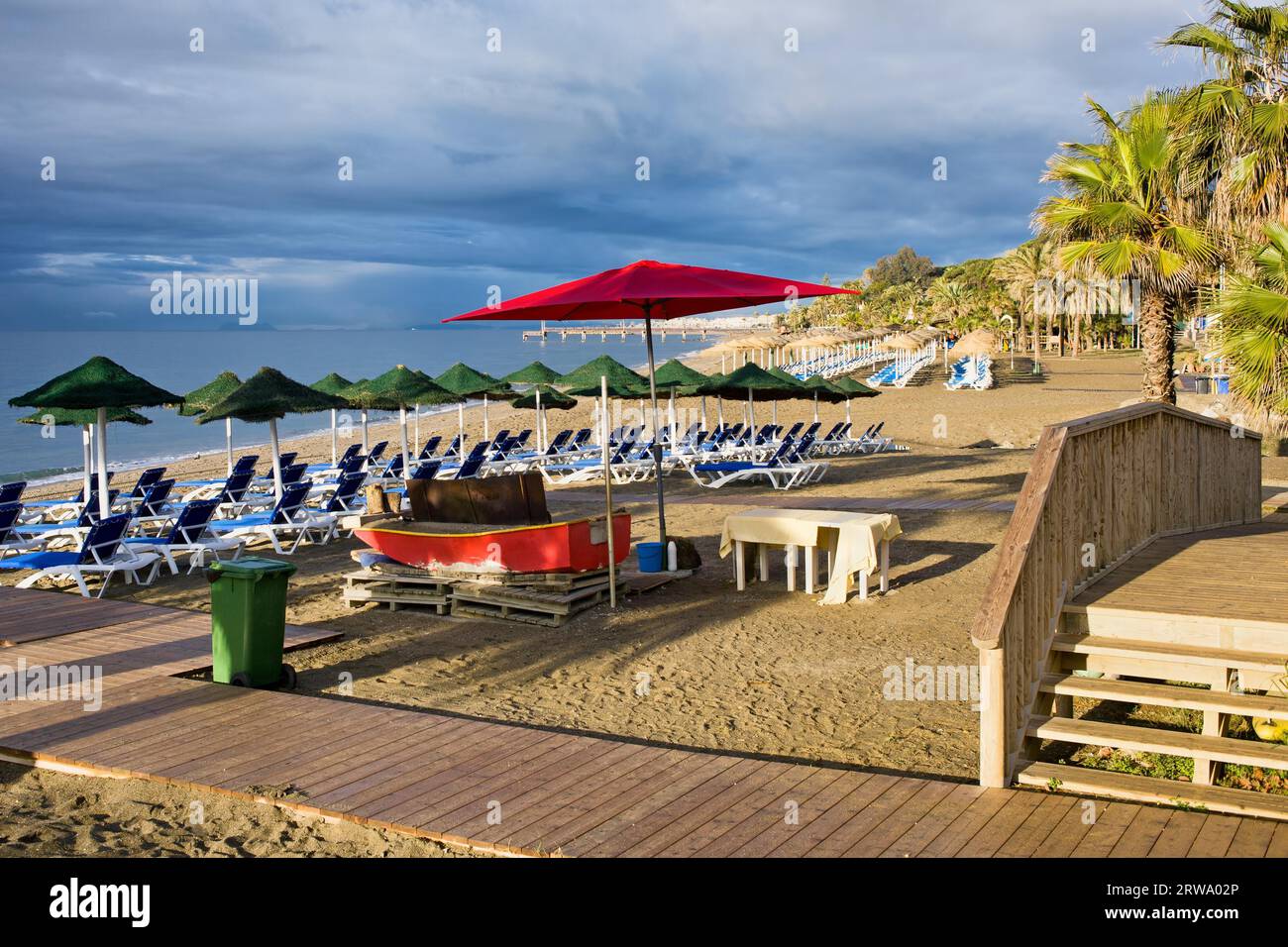 Sun loungers with umbrellas on a beach in the morning at popular resort ...