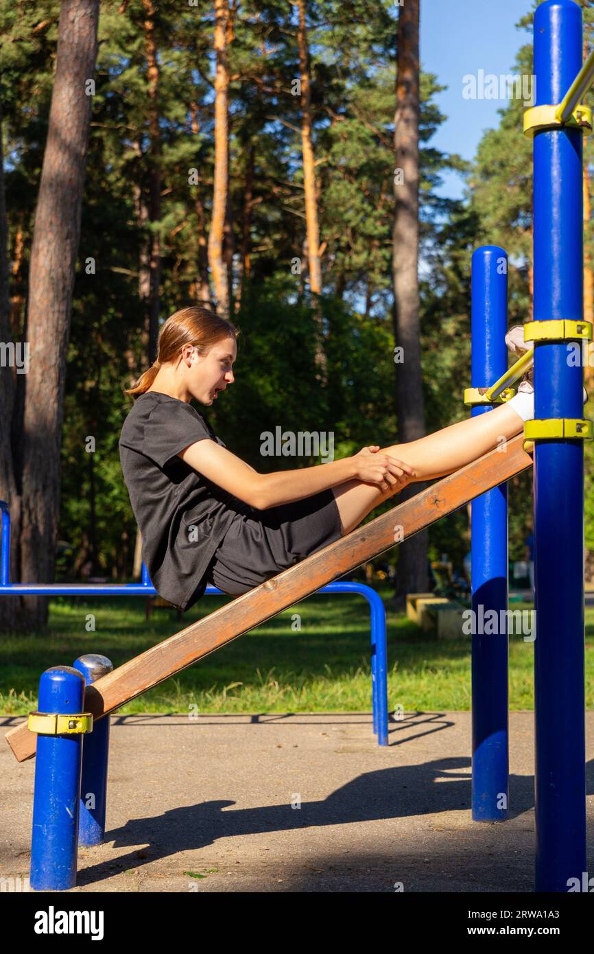 A teenage girl doing abdominal crunches. A girl performs exercises for ...
