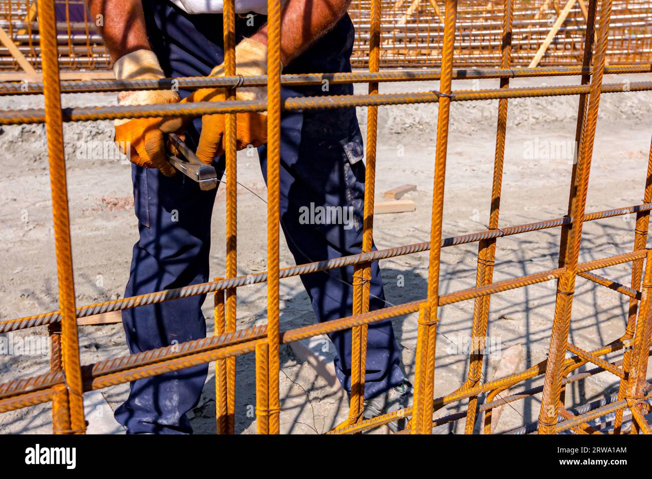 Worker is tying rebar with wire using pliers, to make a reinforcing ...