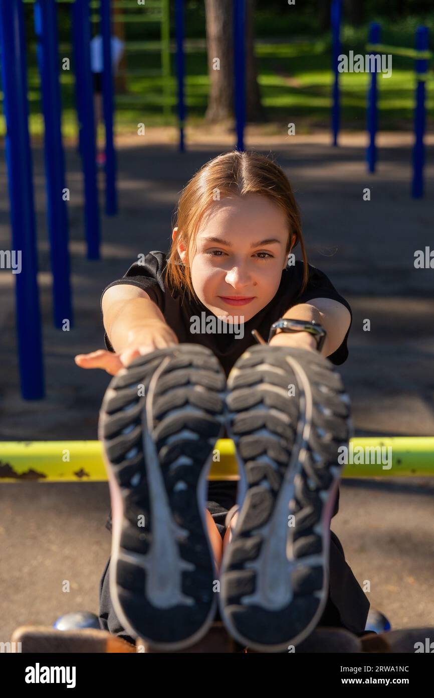 A teenage girl doing abdominal crunches. A girl performs exercises for ...