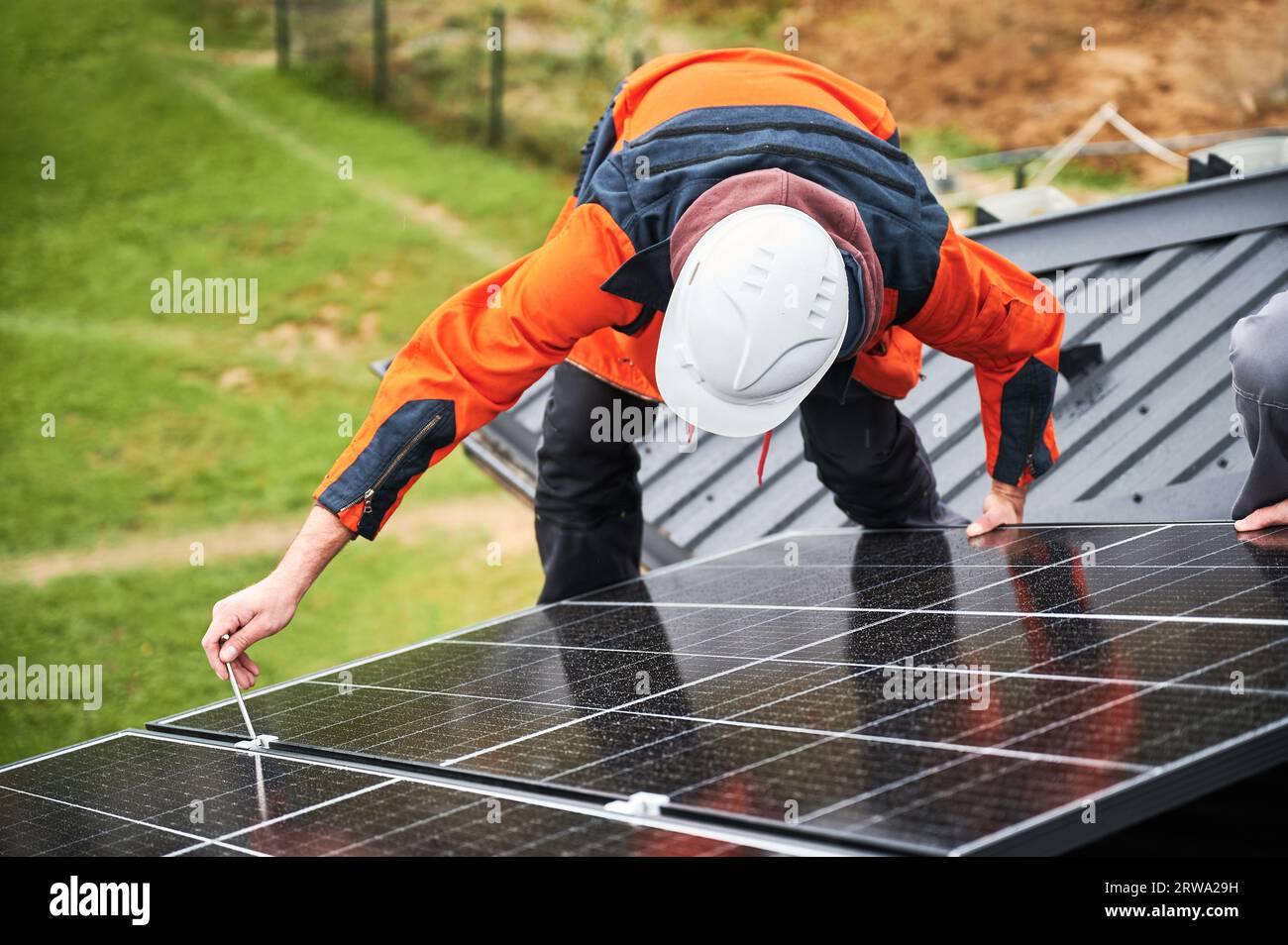 Builders installing photovoltaic solar panels on roof of house. Men ...