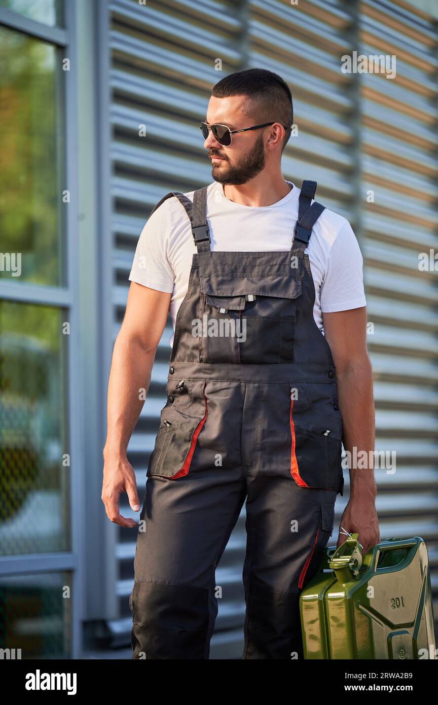 Strong gas station worker holding canister full of fuel. Male operator ...