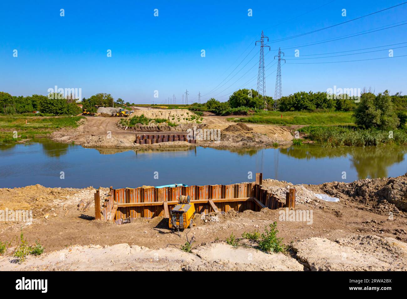 Installed metal piles along river bank, build in for bridge foundation ...