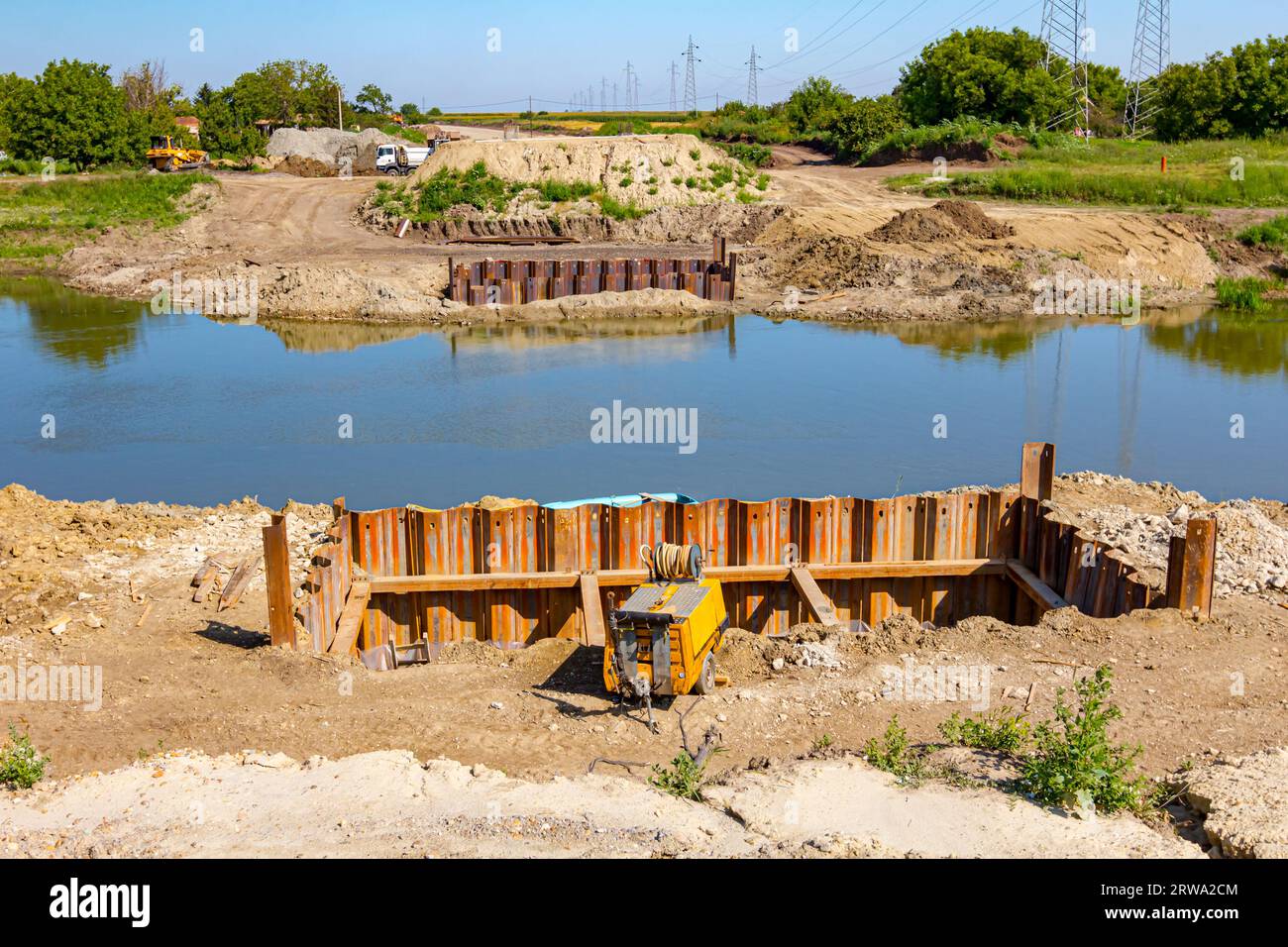 Installed metal piles along river bank, build in for bridge foundation ...