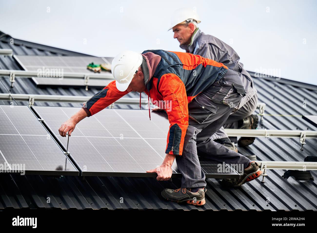 Builders installing photovoltaic solar panels on roof of house. Men ...