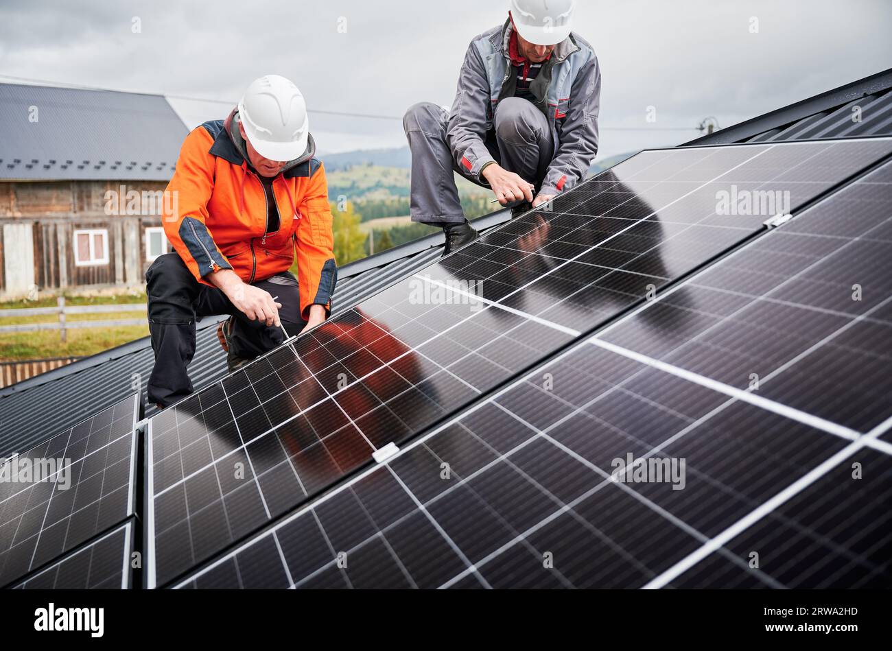 Technicians installing photovoltaic solar panels on roof of house. Men ...