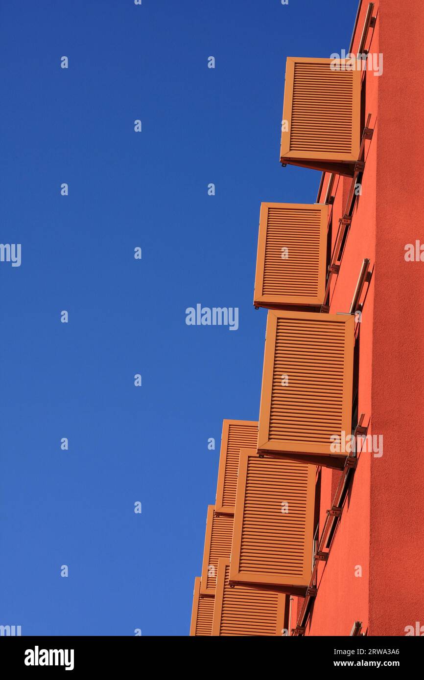 Brown open shutters on a terracotta-coloured house wall of an office ...