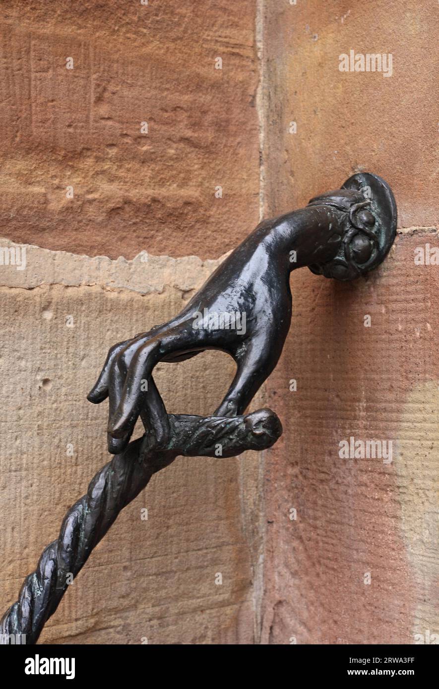 Bronze sculpture on a church wall, hand holding a rope, detail ...