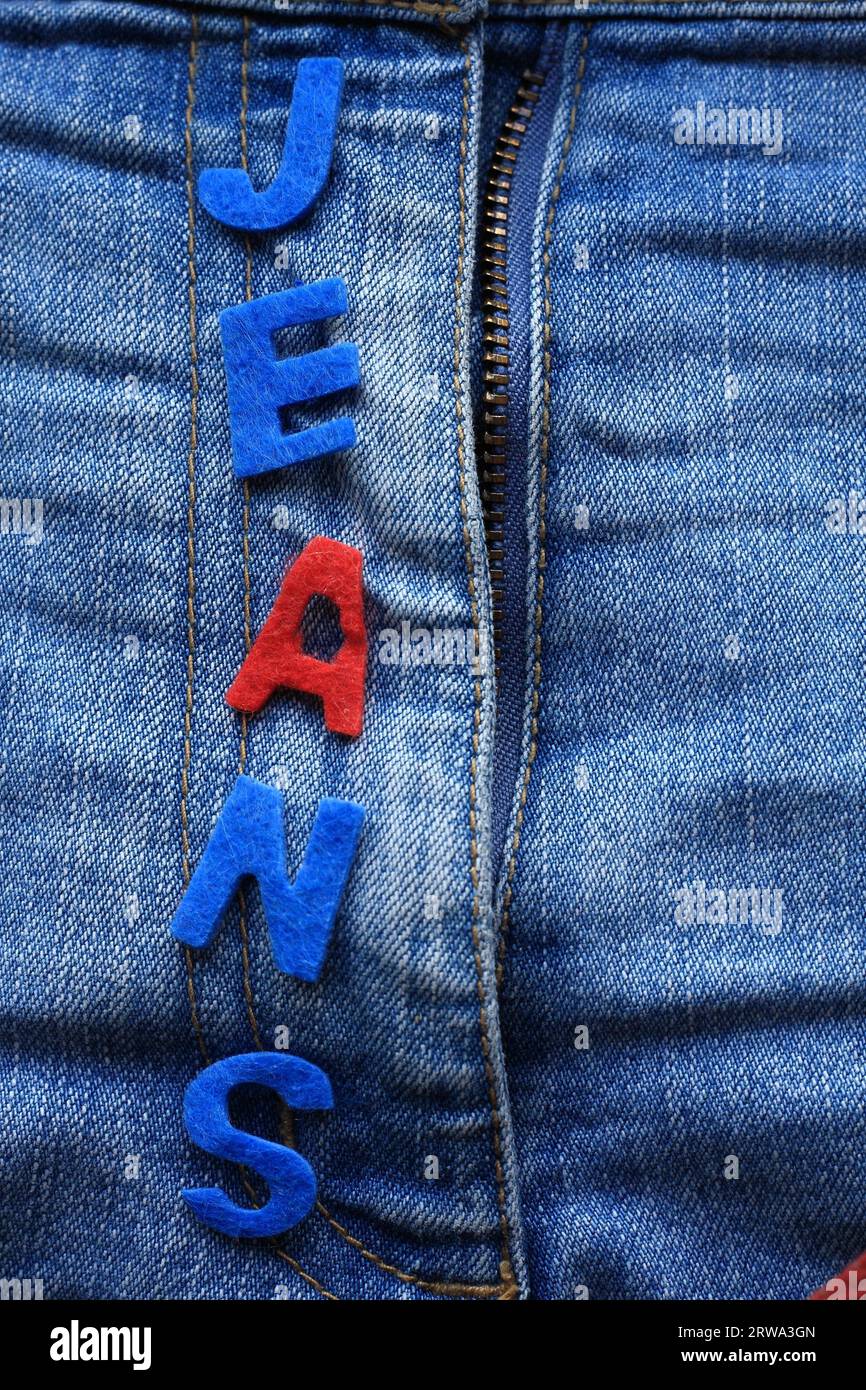 Front of a pair of jeans with zipper, on the left felt letters in blue ...