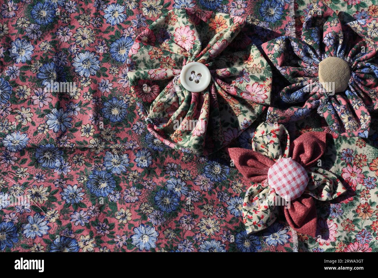 Three fabric flowers with buttons, partly covered made of different ...