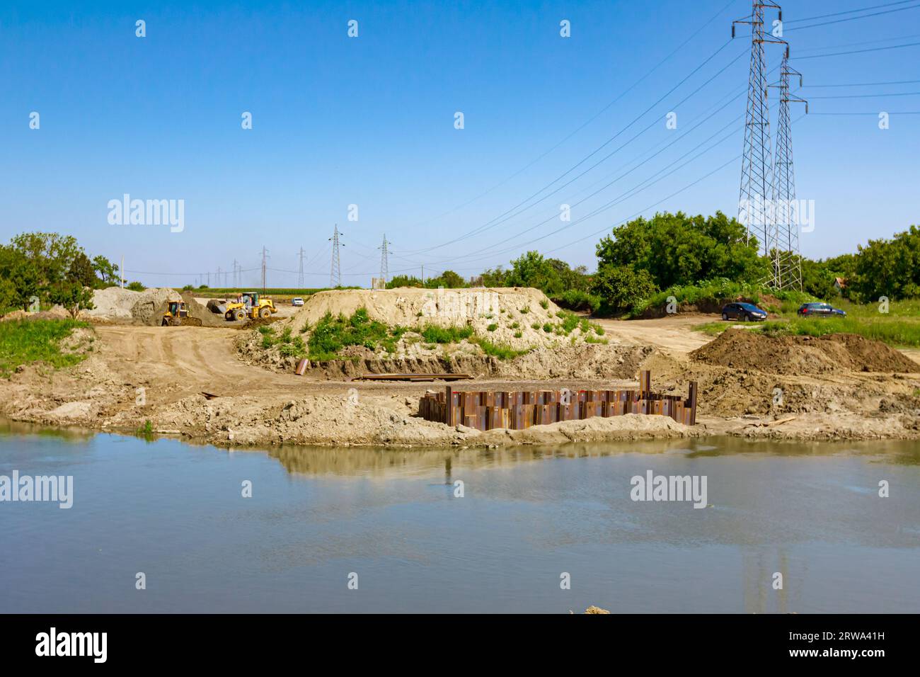 Installed metal piles along river bank, build in for bridge foundation ...