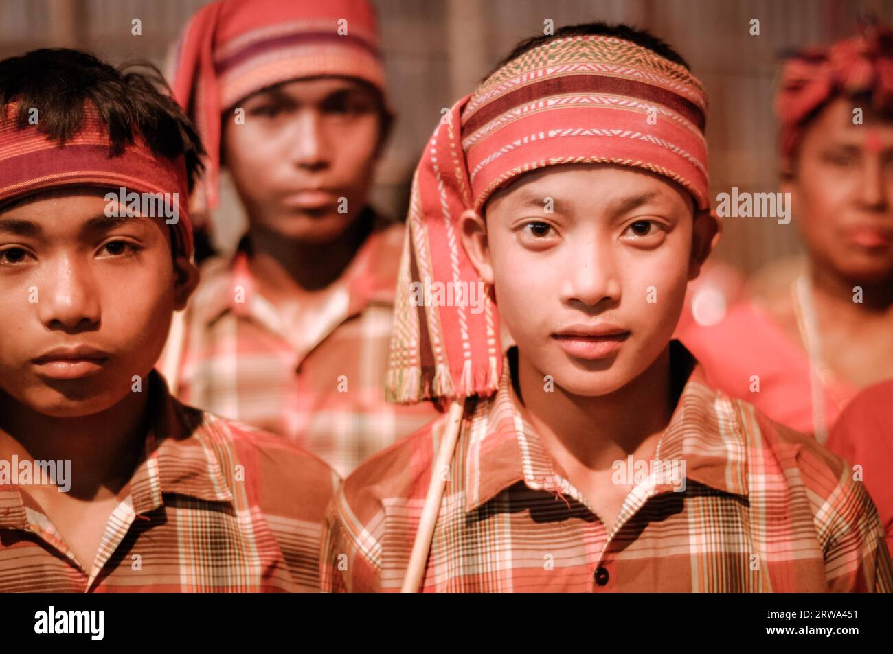 Guwahati, Assam, circa April 2012: Young native boys in orange costumes and with headbands look ...