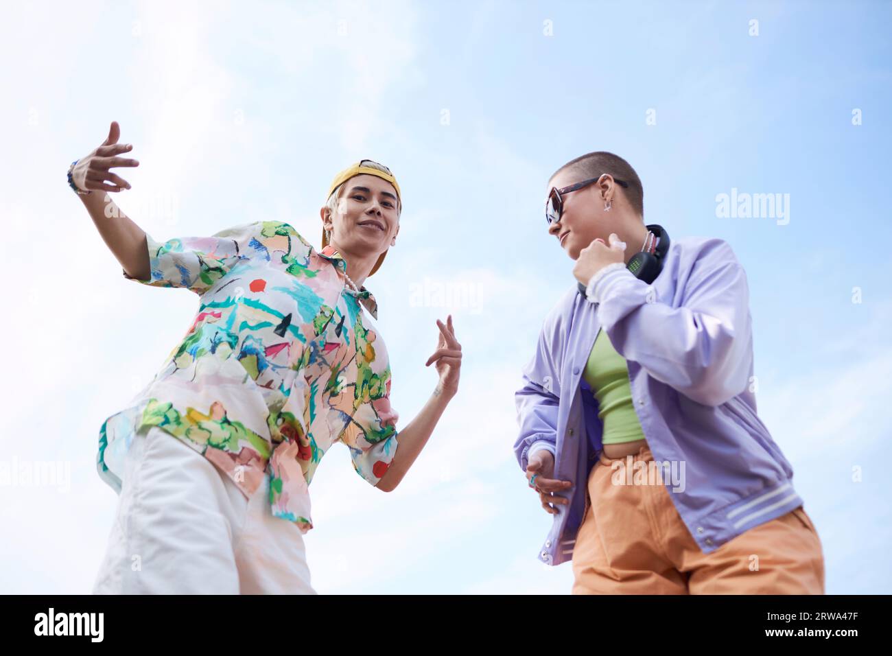 Minimal portrait of two funky young people dancing against clear blue ...