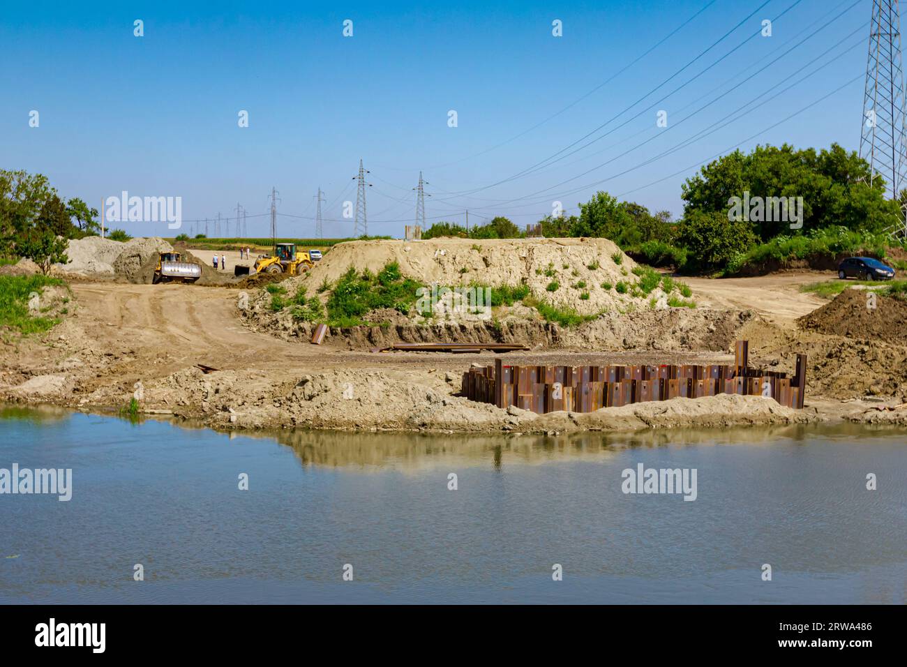 Installed metal piles along river bank, build in for bridge foundation ...