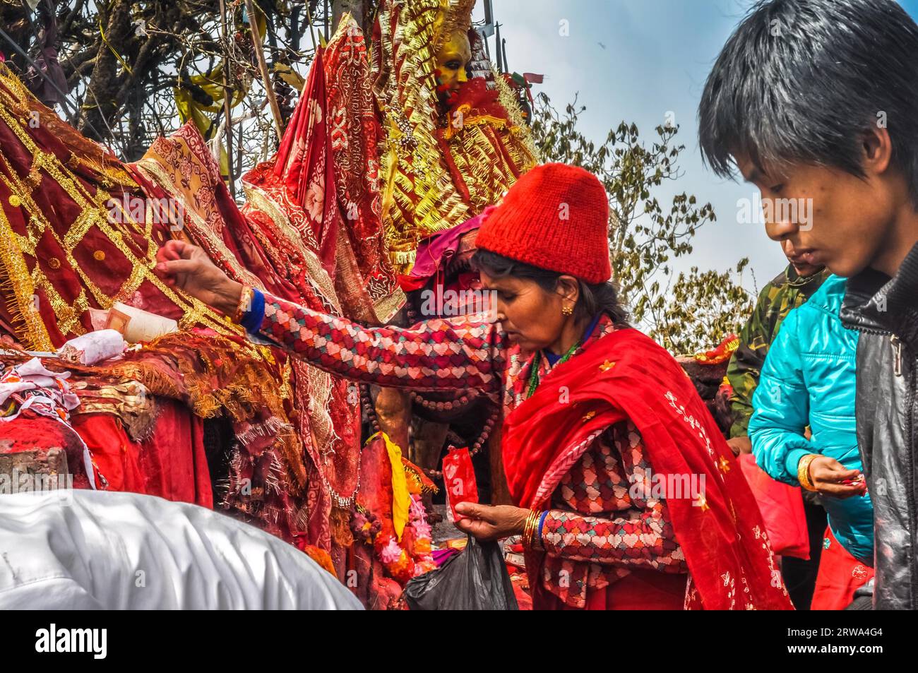 Pathivara Devi, Nepal, circa May 2012: Woman in red clothes touches red ...
