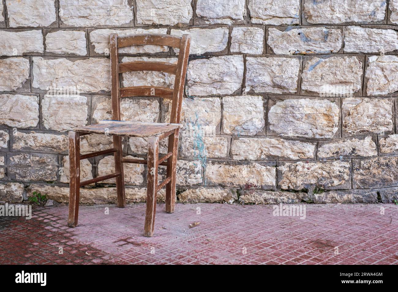 Old wooden chair in front of stone wall Stock Photo - Alamy
