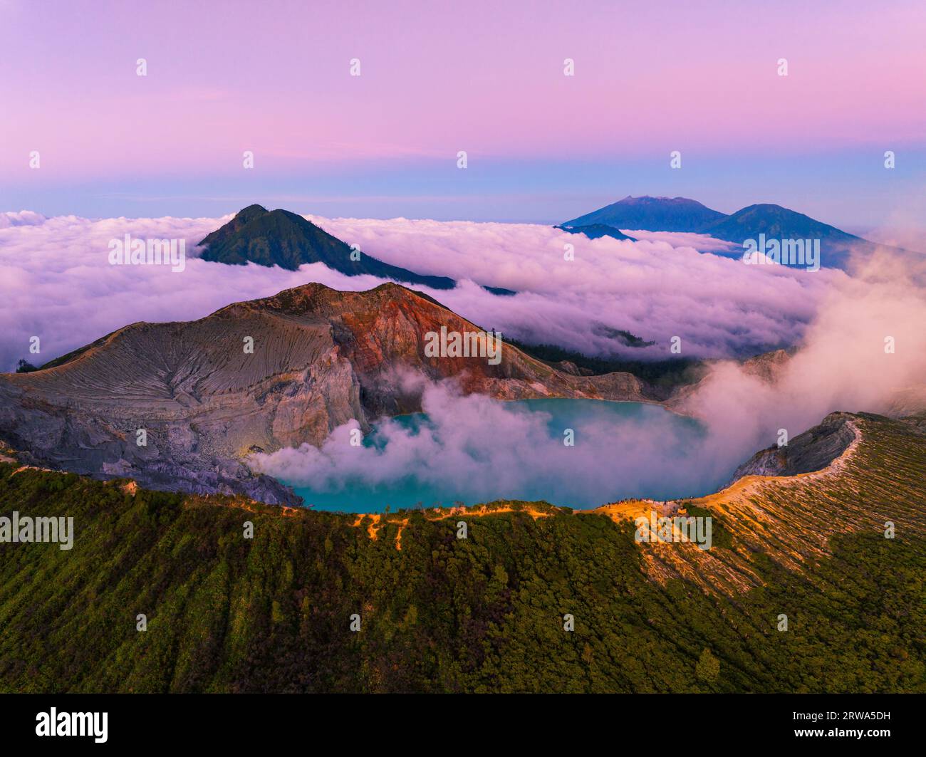 Aerial view of rock cliff at Kawah Ijen volcano with turquoise sulfur water lake at sunrise ...