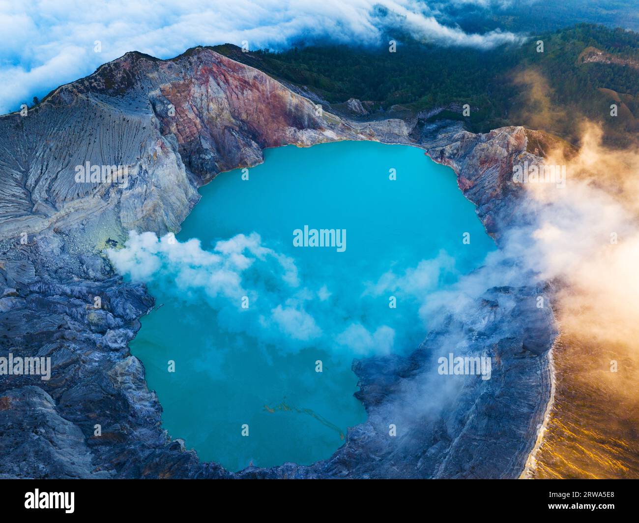 Aerial view of rock cliff at Kawah Ijen volcano with turquoise sulfur water lake at sunrise ...