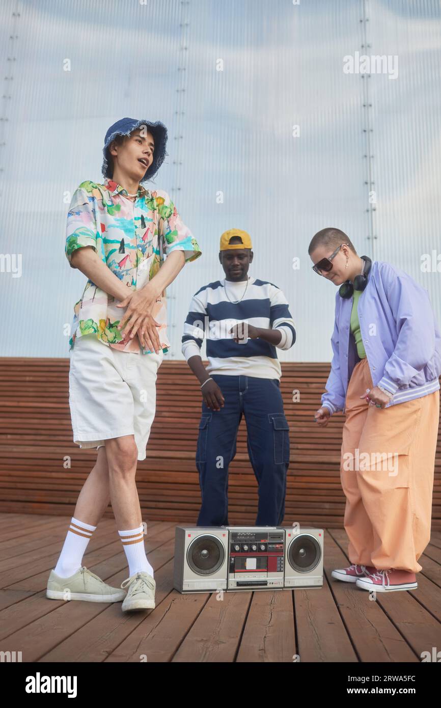 Vertical full length shot of diverse group of young people dancing hip ...