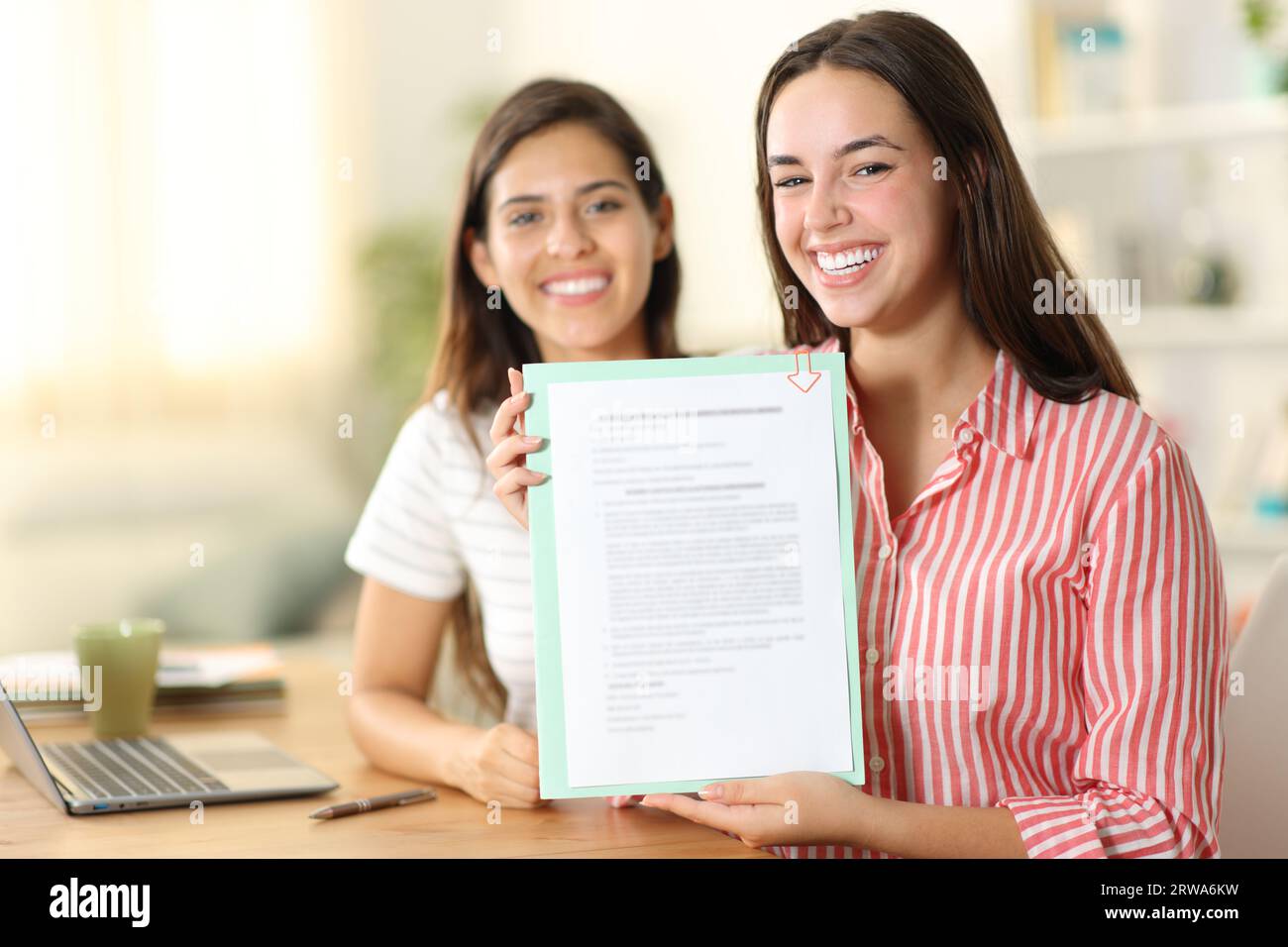 Happy women showing form at camera at home Stock Photo - Alamy