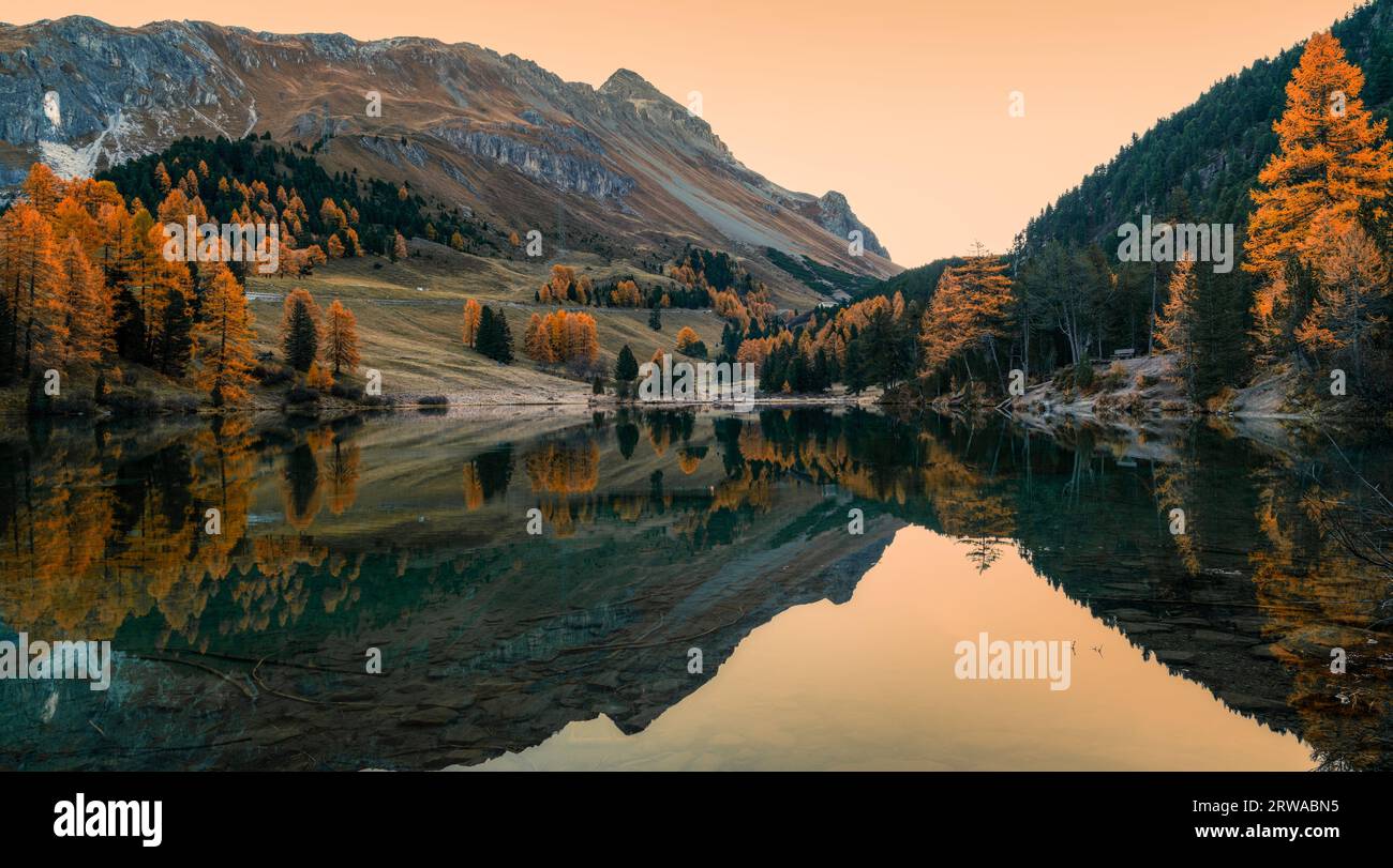 calm mountain lake with reflections of autumn colours in the heart of ...