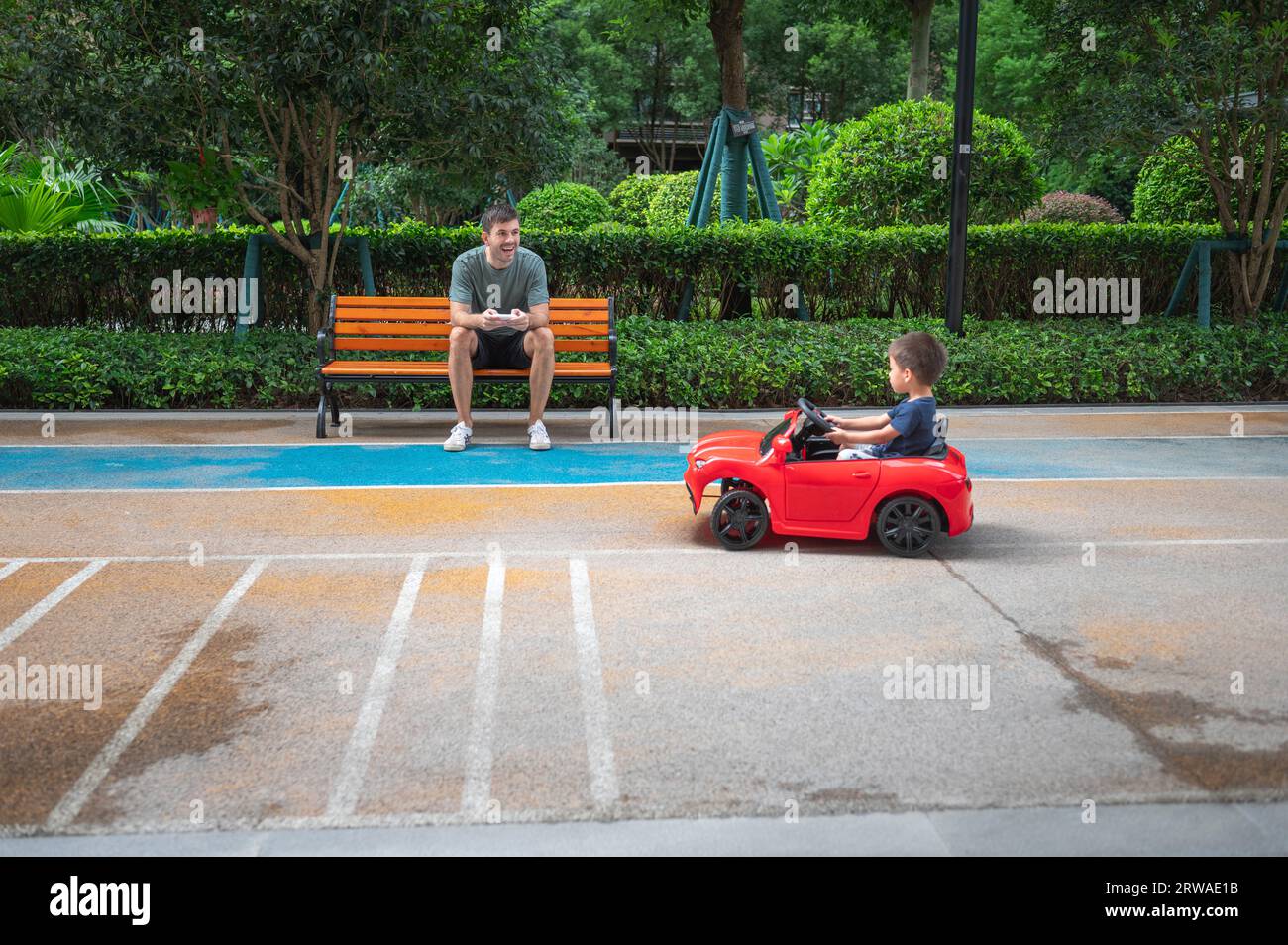 Cute multiracial toddler boy rides in a red remote controlled car while ...