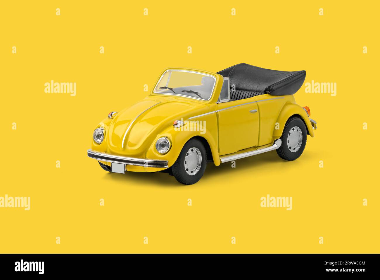 Miniature yellow toy convertible car on a yellow background with copy ...