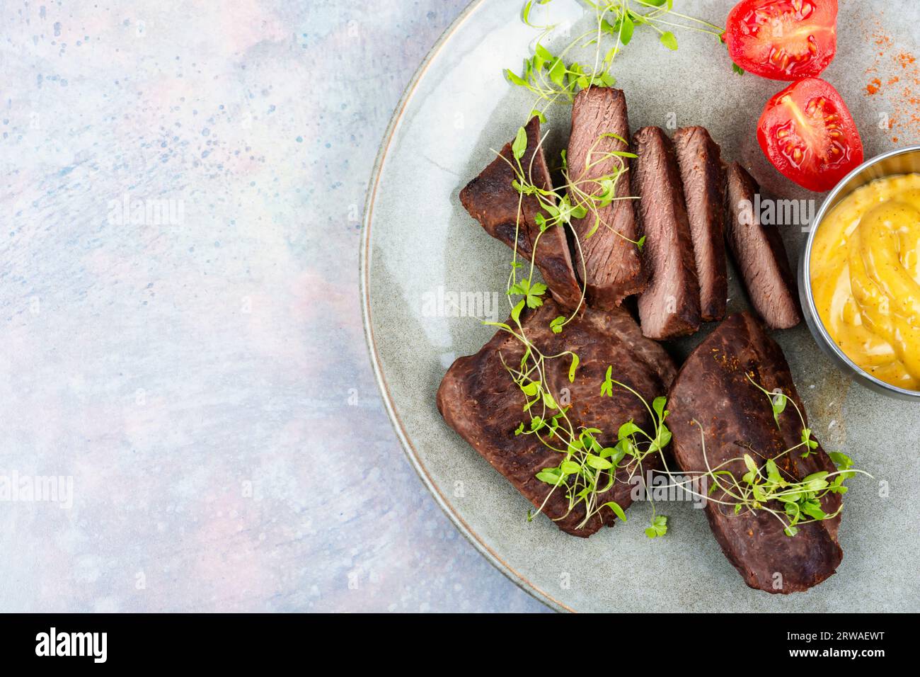 Roasted ostrich steaks with sauce on a plate. African food. Space for ...