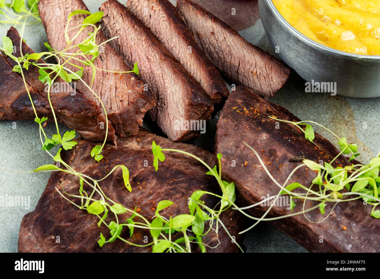 Roasted ostrich meat steaks with sauce and microgreens. African cuisine ...