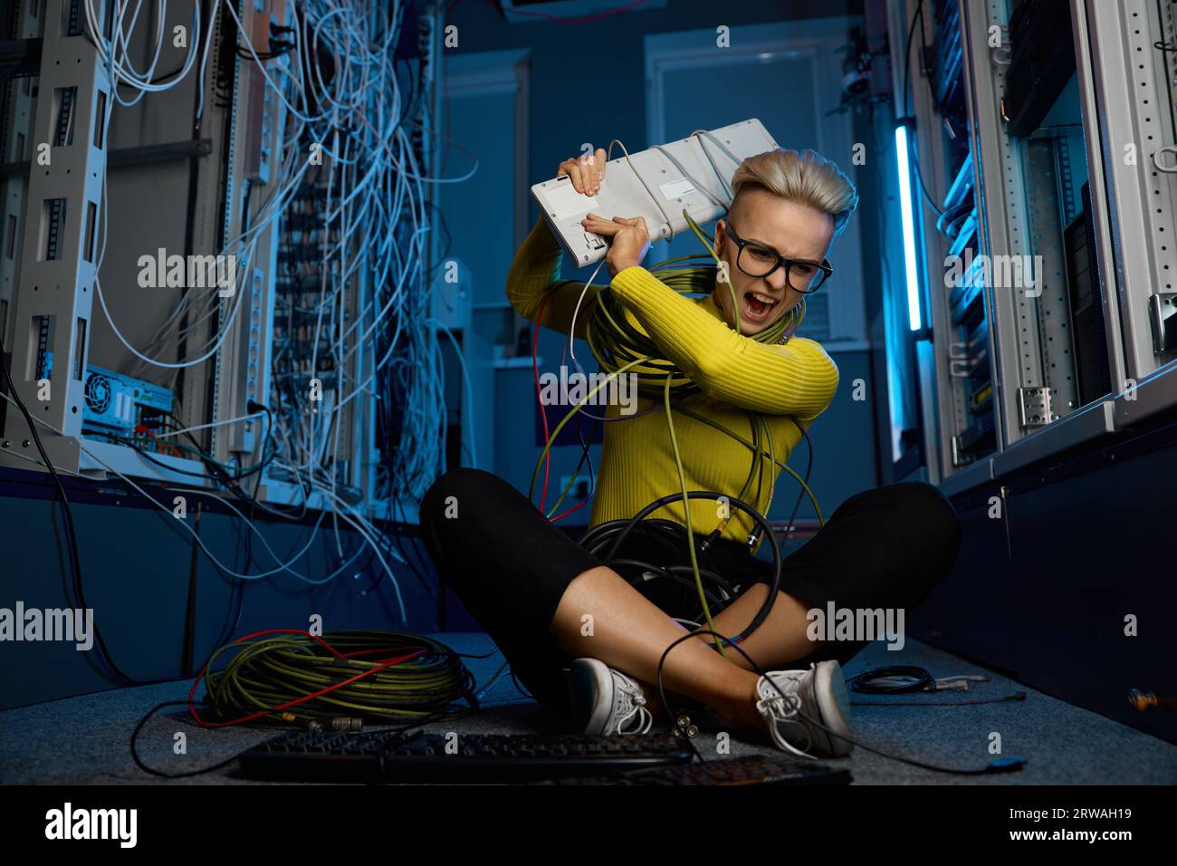 Frustrated angry female IT technician throwing computer keyboard in ...