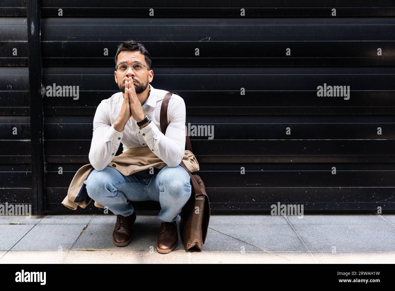 Young stressed and depressed businessman squat down outside office ... Young stressed and depressed businessman squat down outside office ...