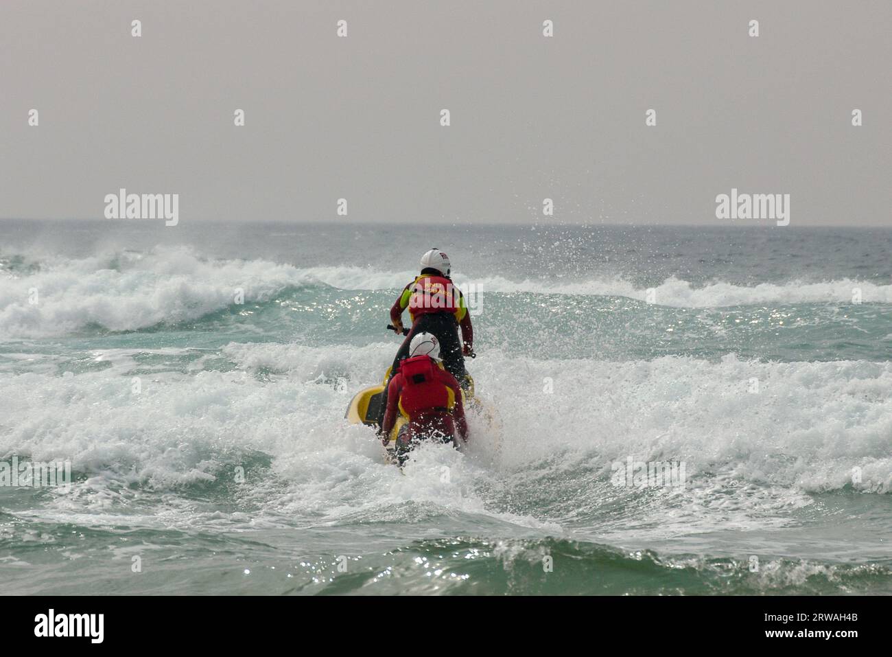 RNLI lifeguard member on Jet ski with another on a rescue sled heading ...