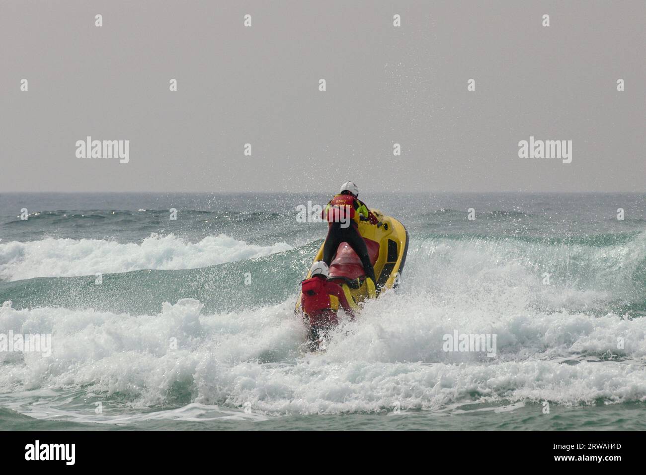 RNLI lifeguard member on Jet ski with another on a rescue sled heading ...