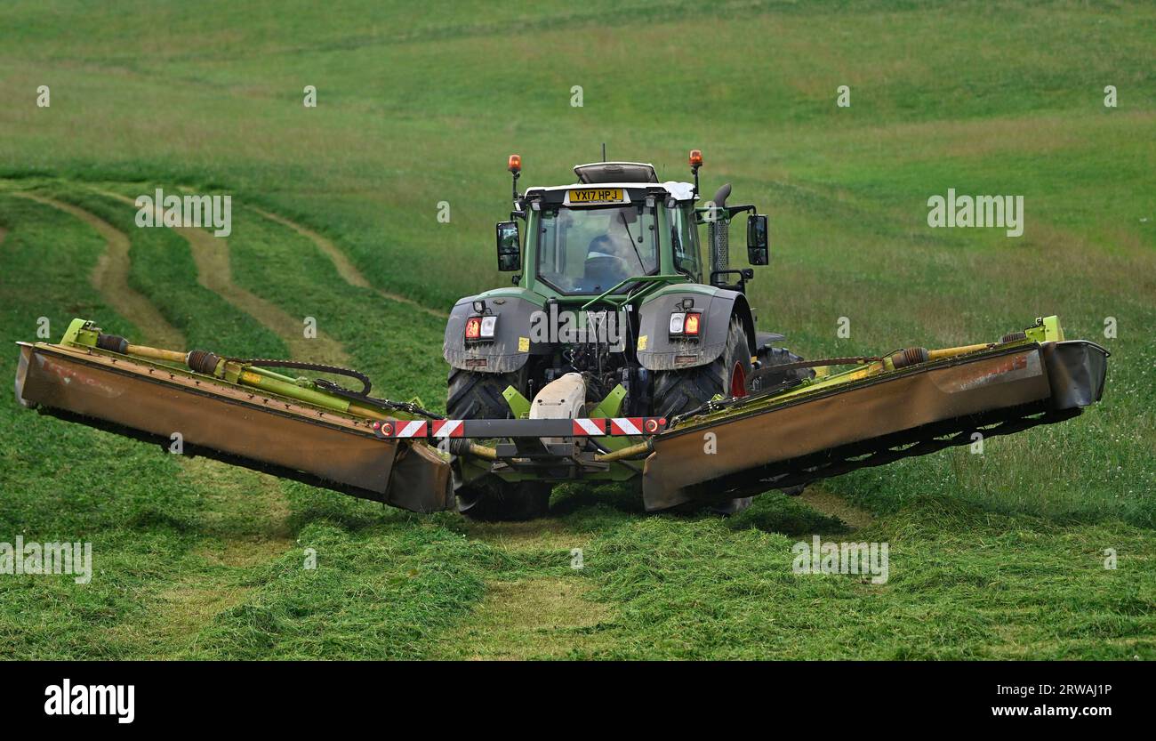 Tractor in field cutting the grass for silage with the grass cutters ...