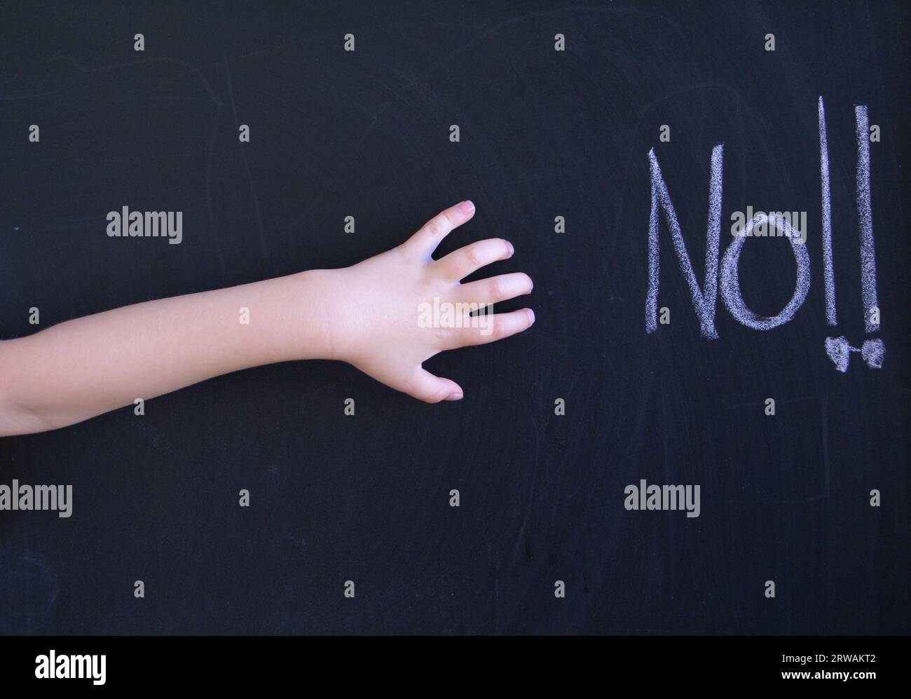 Close-up of a child's hand scratching fingernails across a blackboard ...