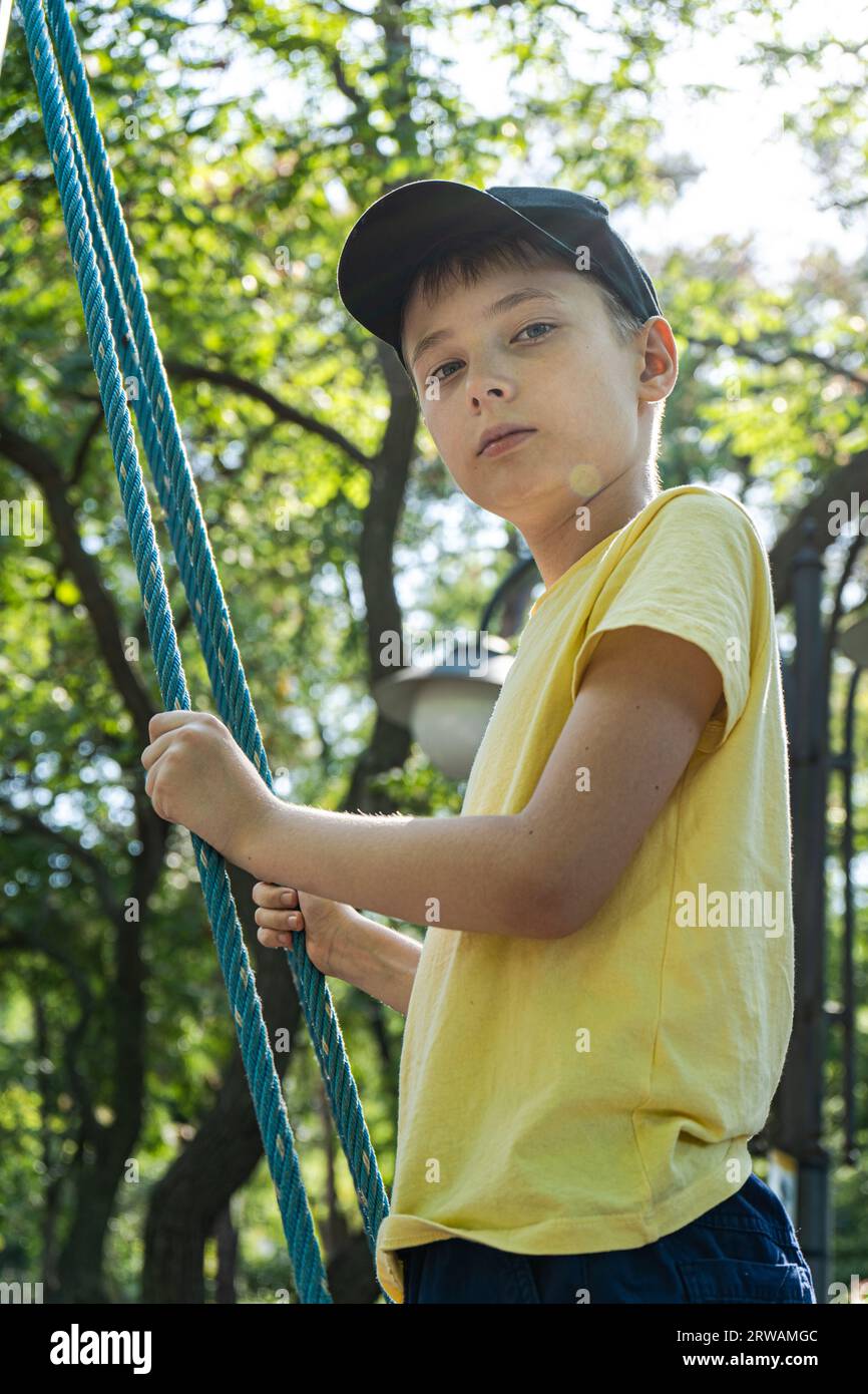 Boy climbing on a rope climbing frame in a playground in summer ...