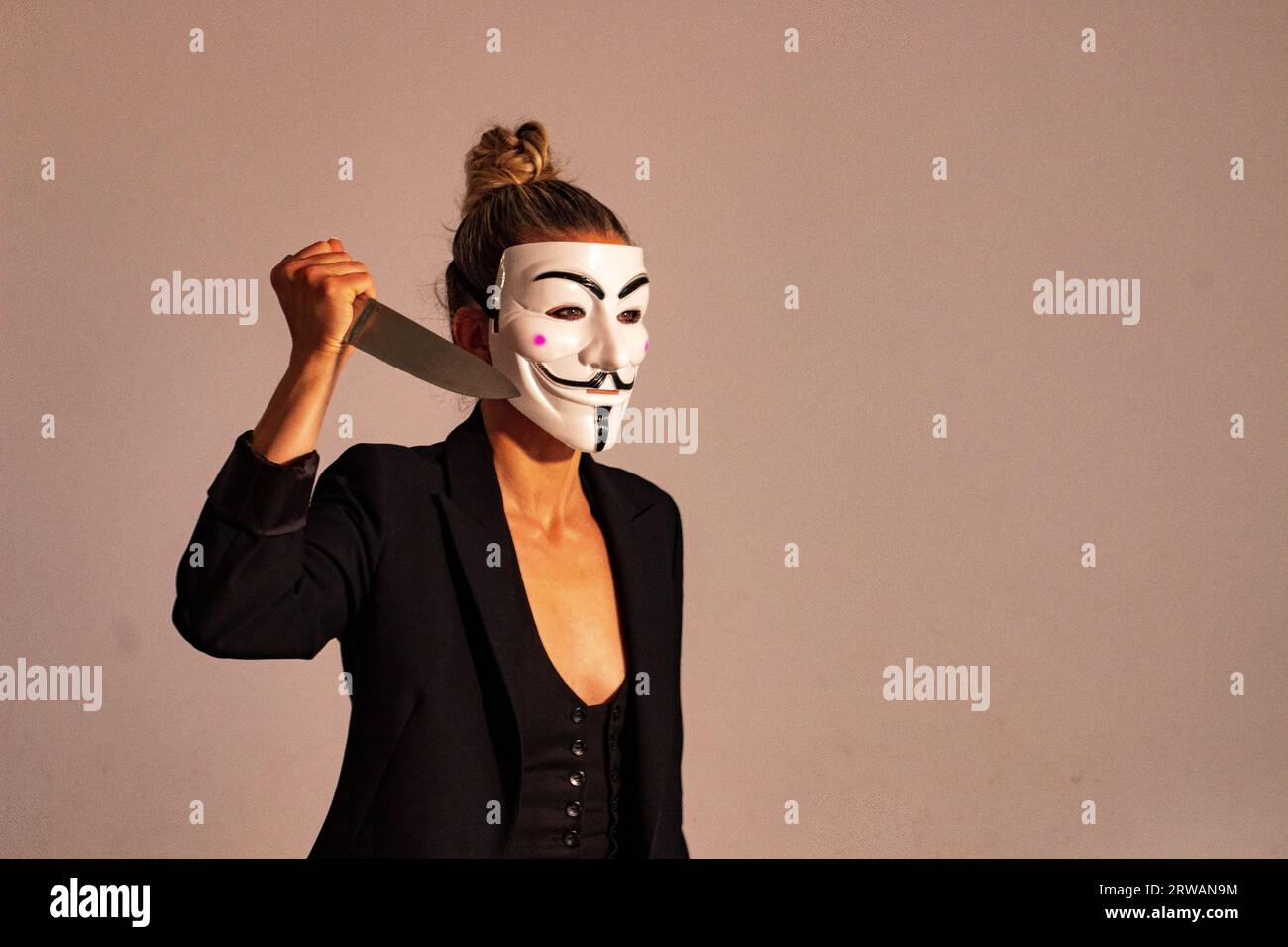 Woman with an anonymous mask dressed in a black colored suit jacket ...