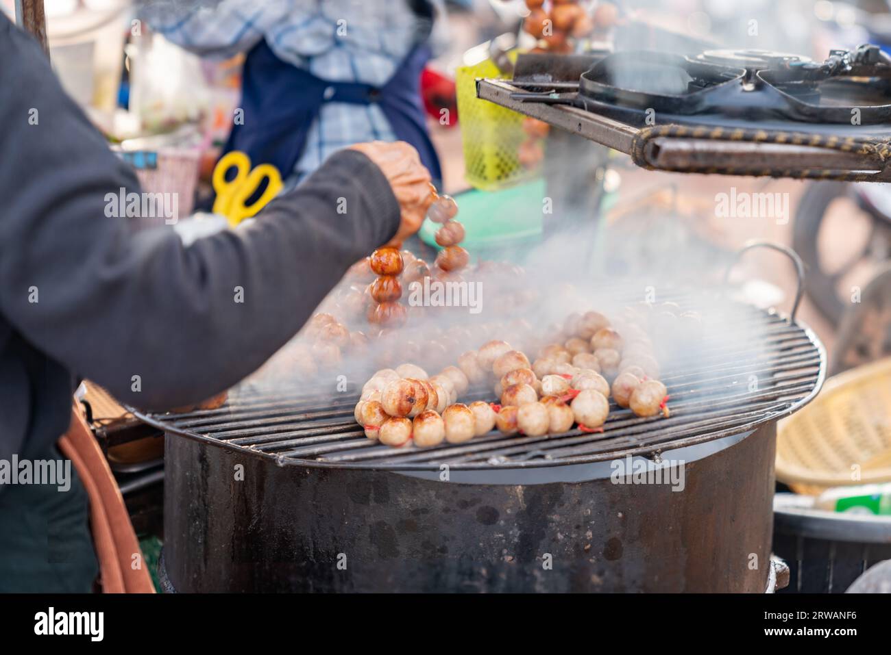 Food seller grill sausage on street food market and exhaust fan suck ...