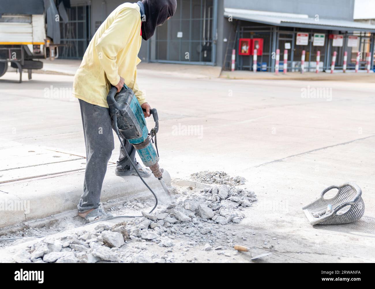 Worker in factory demolishing concrete floor with electric plugger ...
