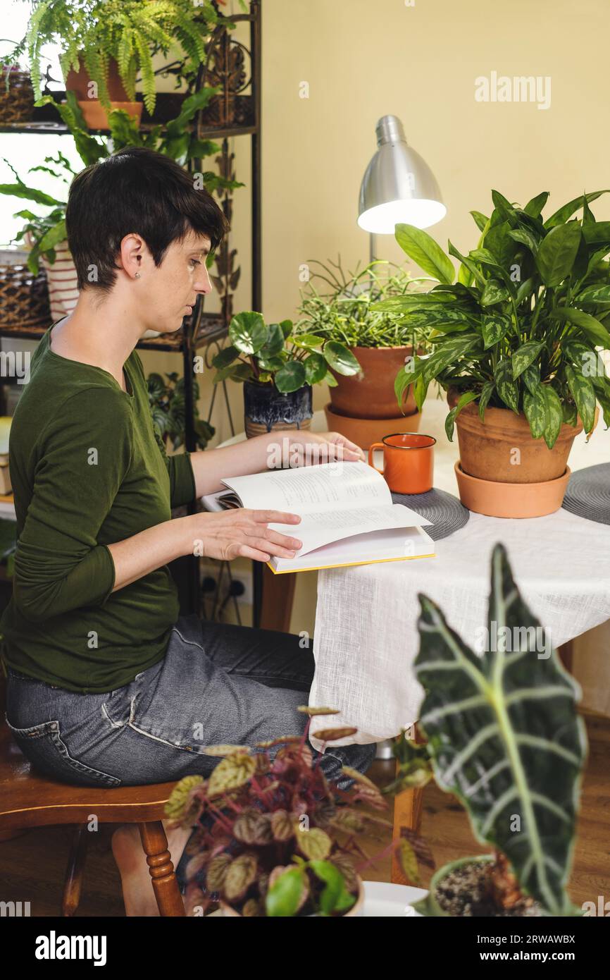 Woman at her reading place near houseplants. Green relax zone in the ...