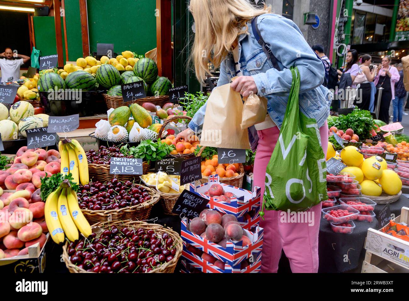 London, UK. Borough Market, Southwark. Woman shopping at a fruit stall ...