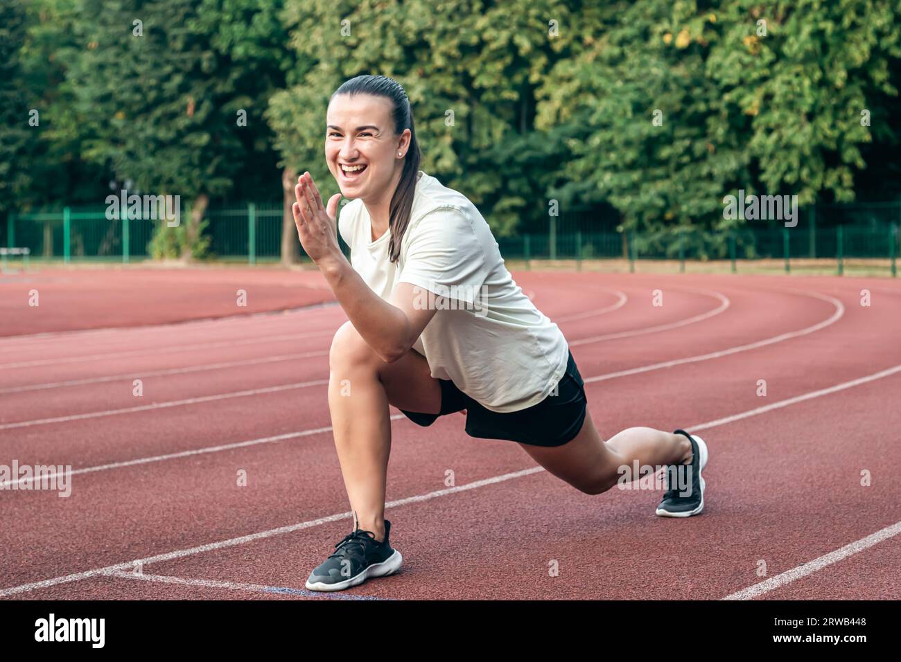 A young woman runner in start position on running track while work out ...